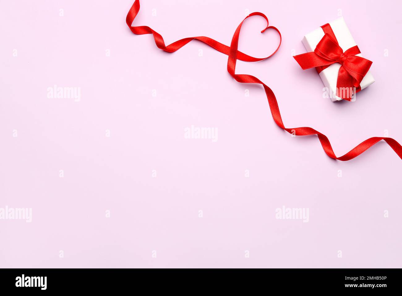 Gift and heart made of red satin ribbon on pink background. Valentine's ...