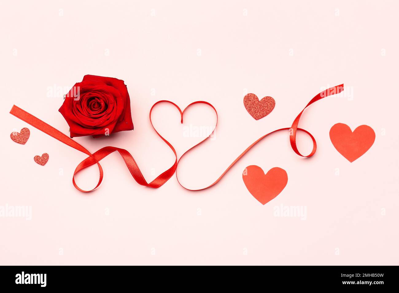 Rose flower and heart made of red satin ribbon on pink background ...