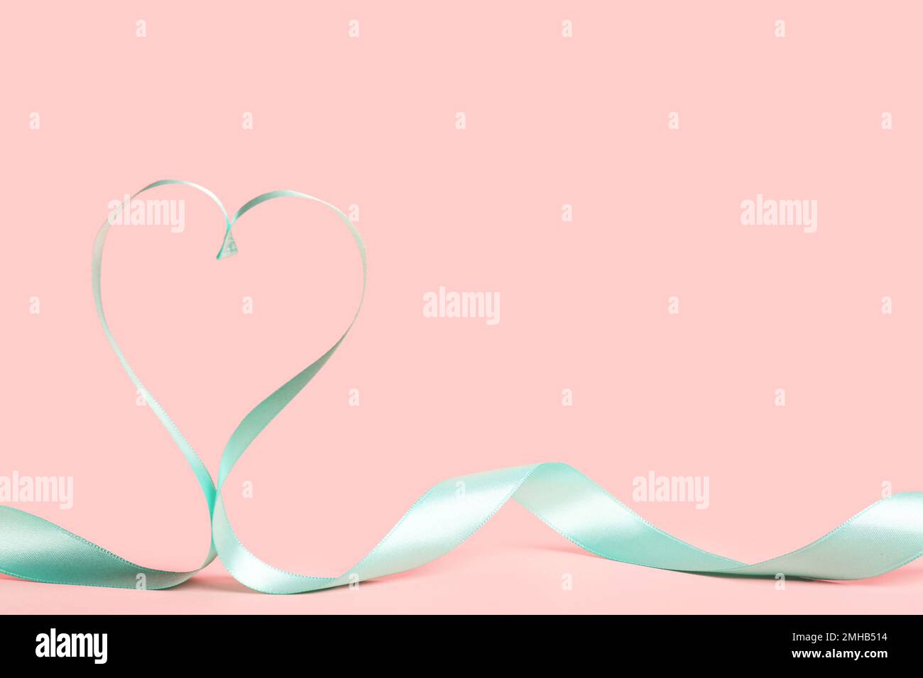 Heart made of turquoise satin ribbon on pink background. Valentine's ...