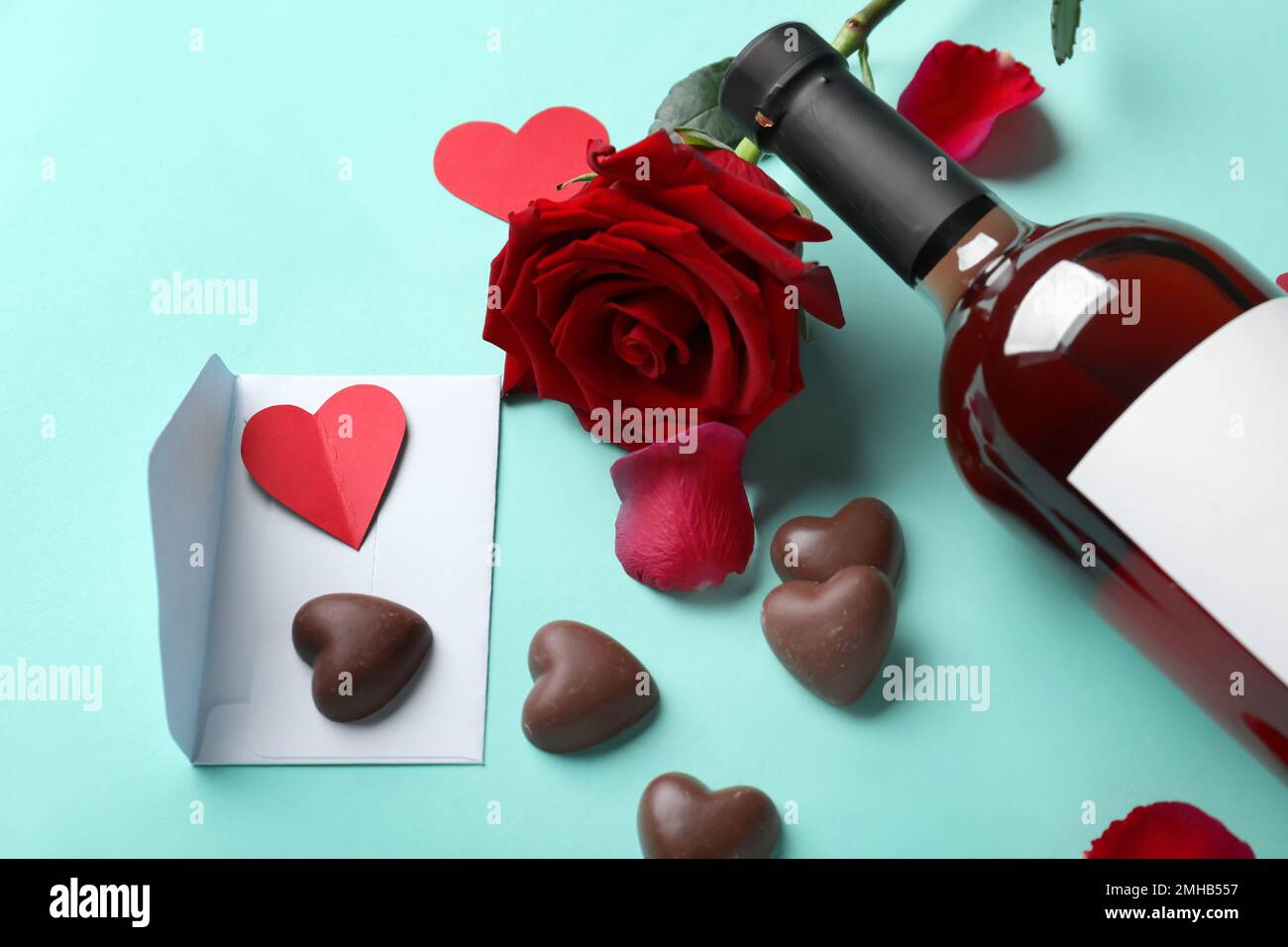 Bottle of wine, chocolate candies, rose flower and envelope on ...