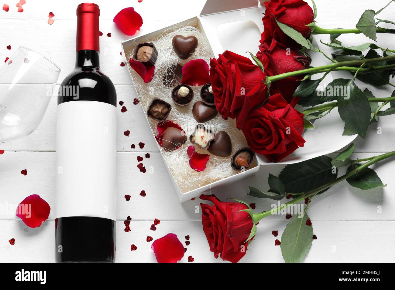 Bottle of wine, box with candies and rose flowers on white wooden ...