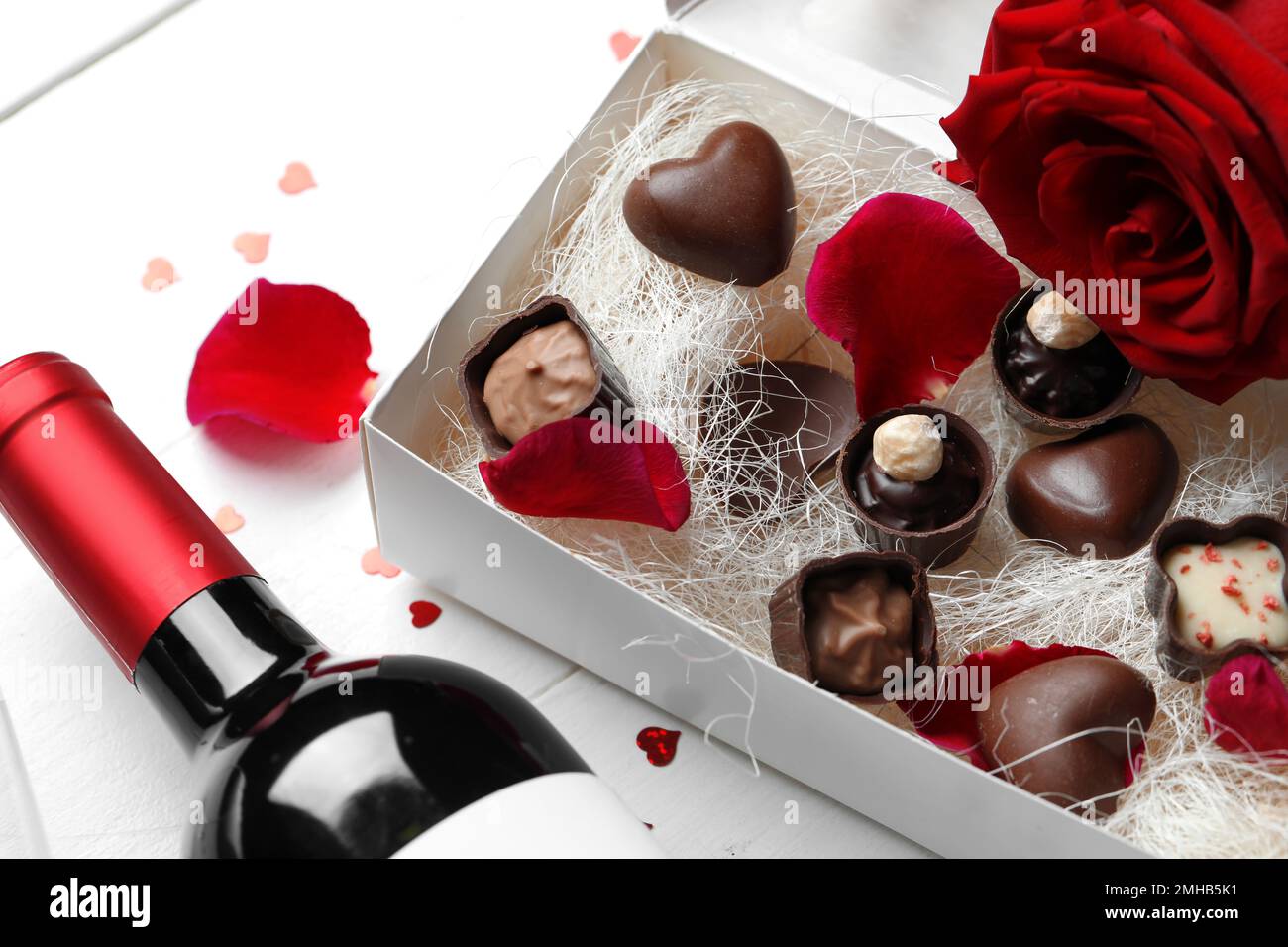 Bottle of wine, box with candies and rose flowers on white wooden ...