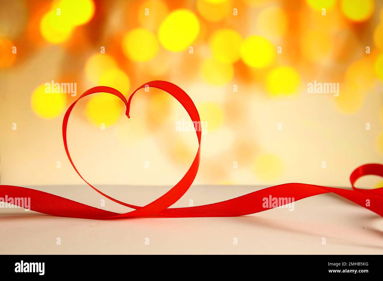 Heart made of red satin ribbon on table against blurred lights Stock ...