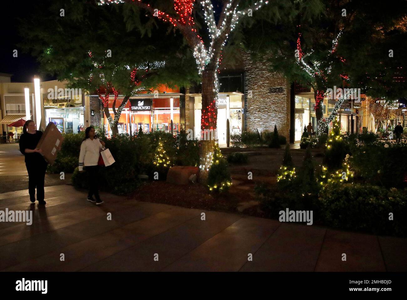 Shoppers walk past trees illuminated for the holiday season Monday, Dec ...