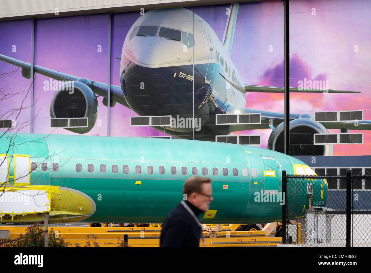 A Boeing worker walks past a 737 model fuselage and a giant mural of a ...