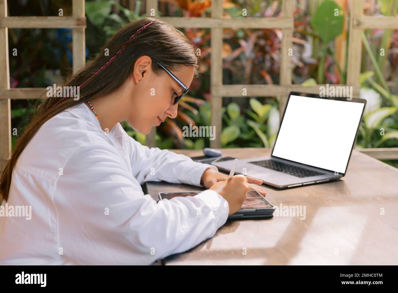 Woman designer using digital tablet and laptop computer in summer ...