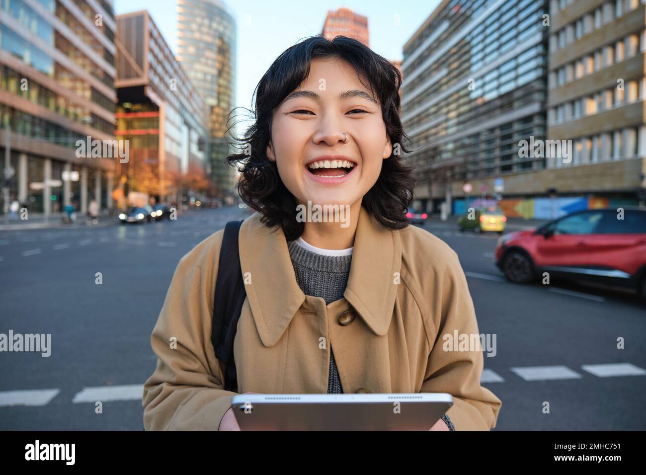 Portrait of asian girl student, stands in city centre with cars on busy ...