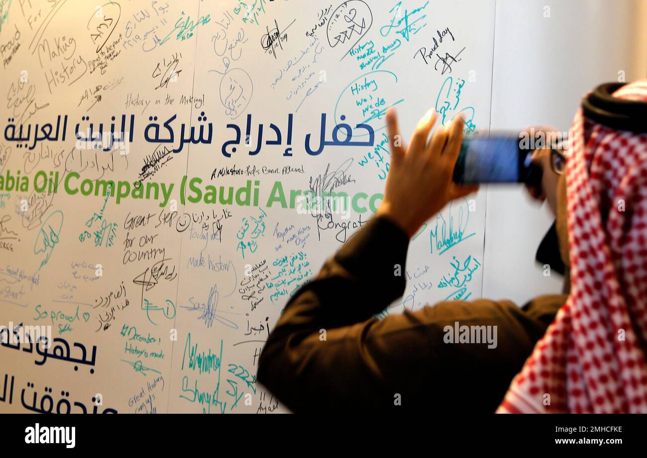 A Saudi stock market official films a banner of Saudi Arabia's state ...