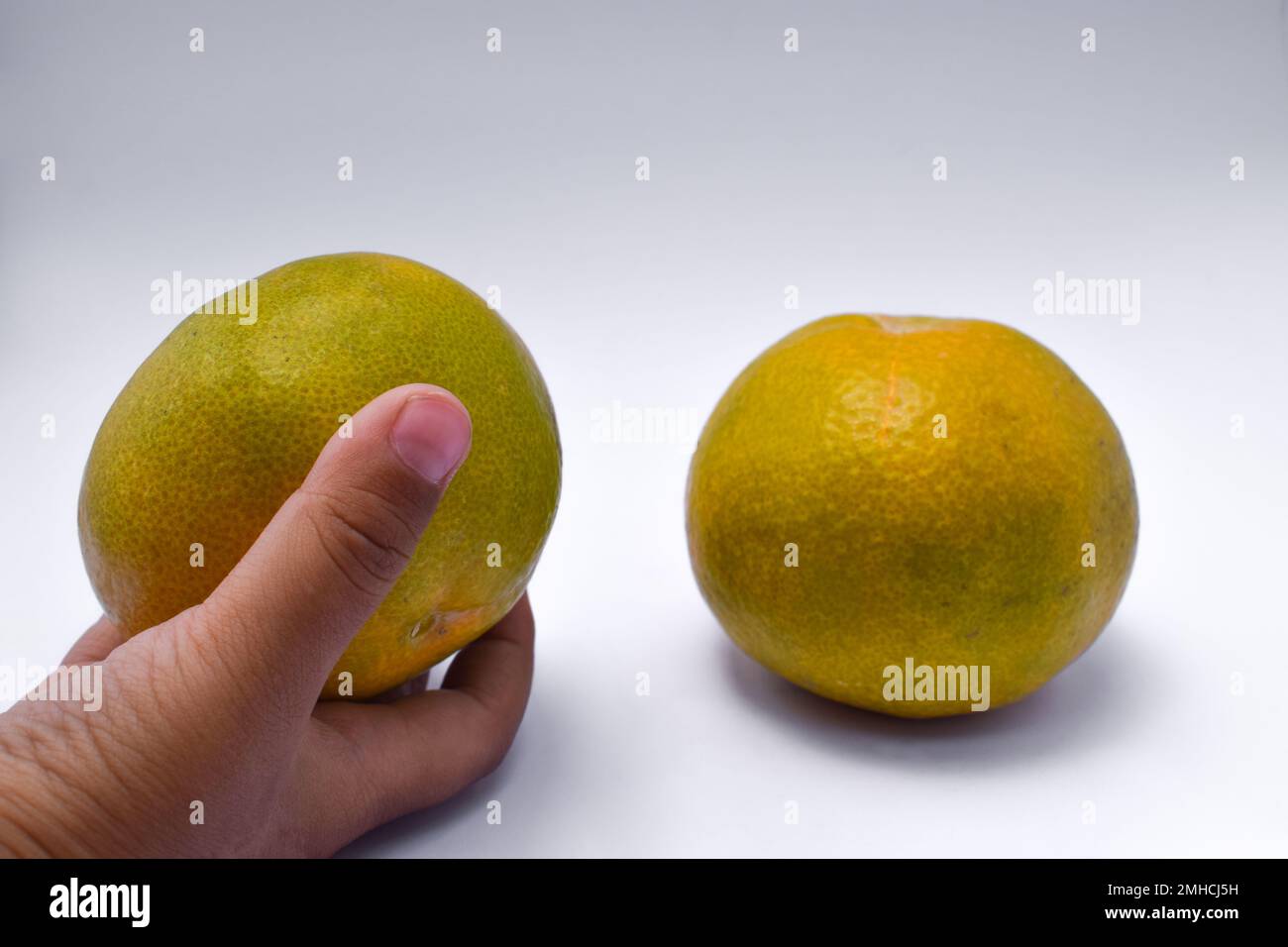 A hand picks up an orange on a white background Stock Photo - Alamy