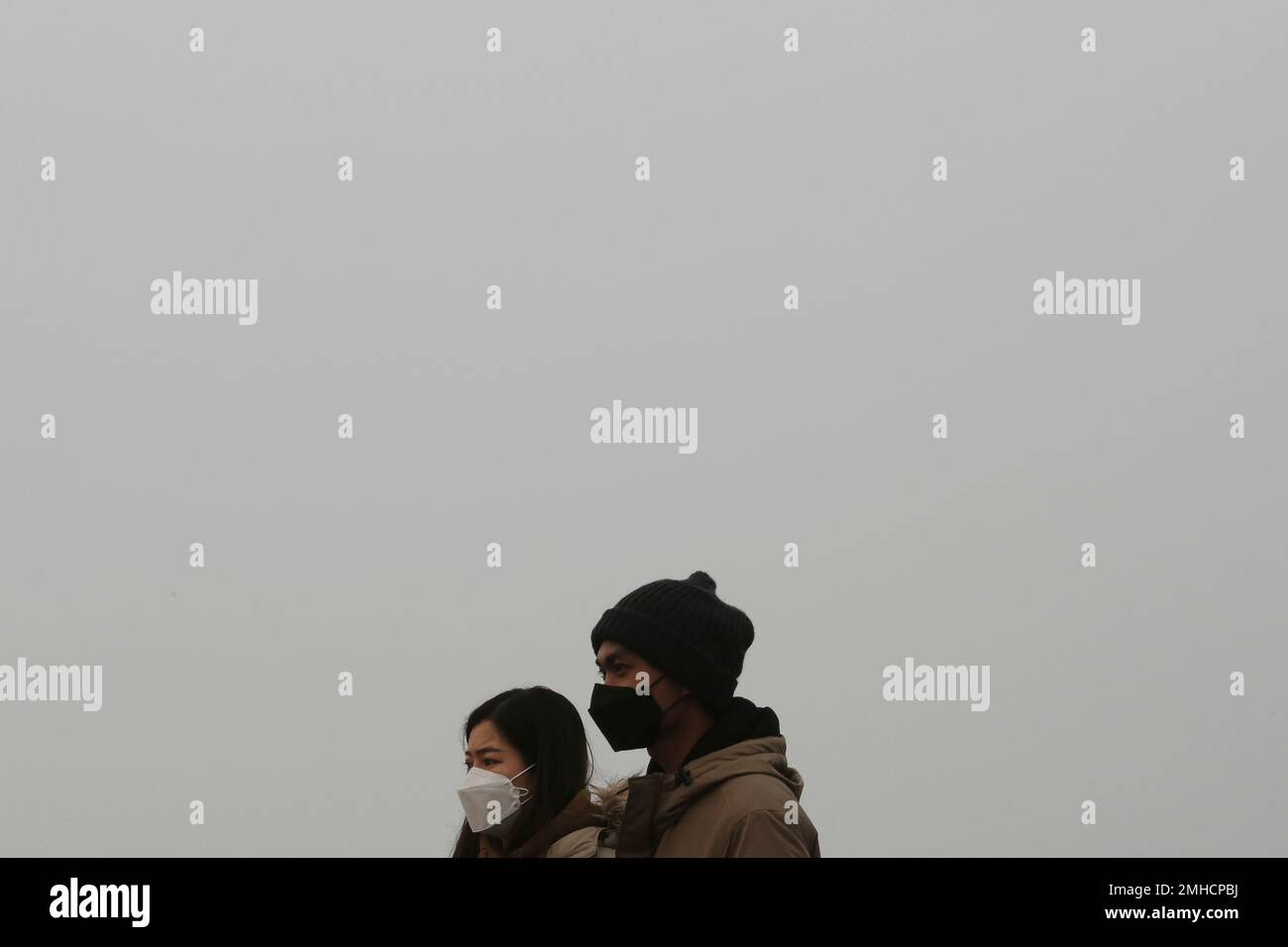 A couple wearing masks to protect themselves from air pollution walks ...