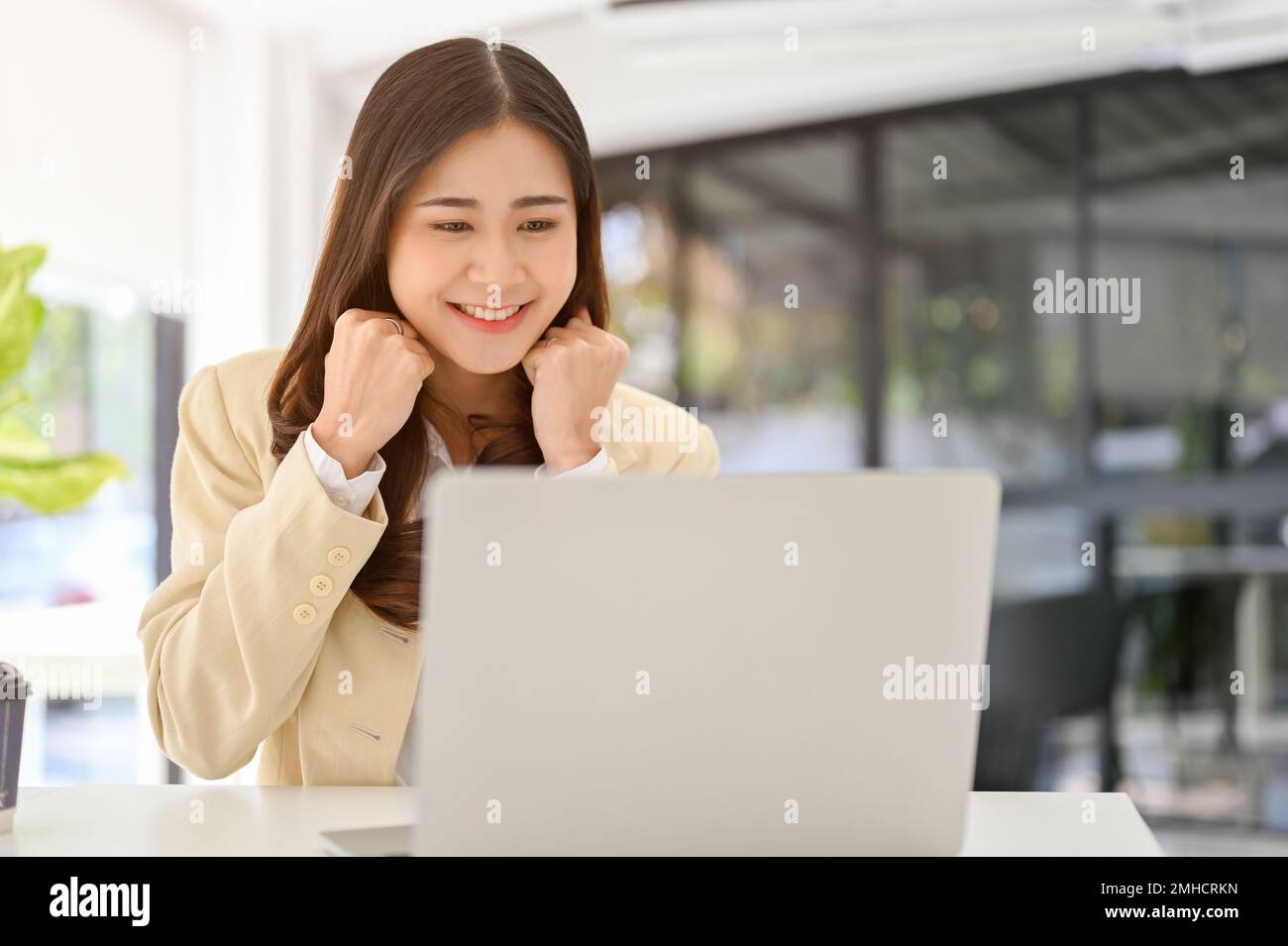 Happy and excited Asian businesswoman looking at laptop screen ...