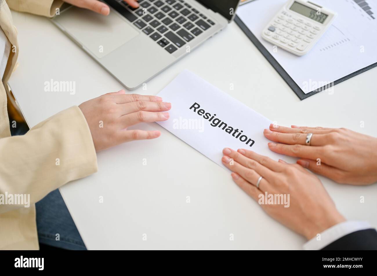 A businesswoman sending a resignation letter to her boss at the desk ...