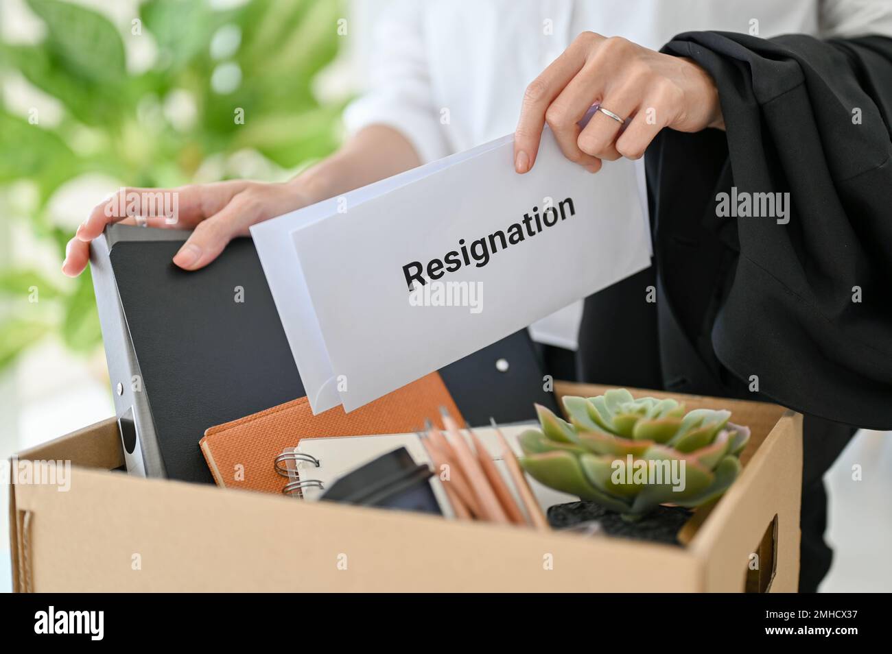 A businesswoman with a resignation letter in her hand and her stuff in ...