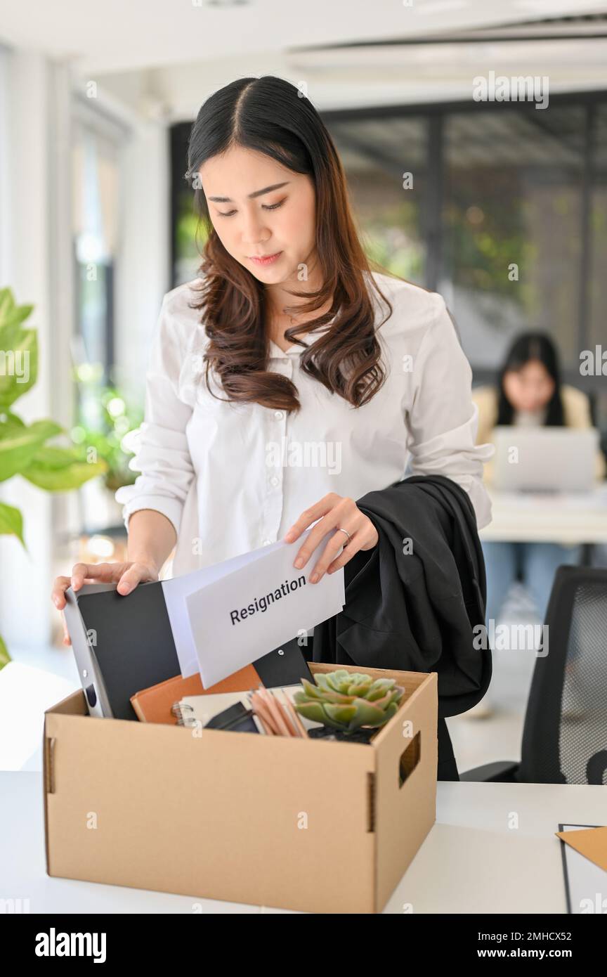 Sad and unhappy young Asian female office worker with a resignation ...