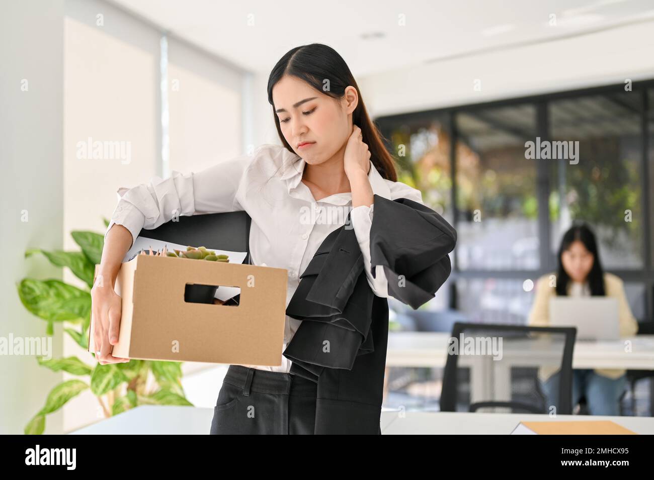 Sad young Asian female office worker carrying her personal stuff in the office. being fired ...