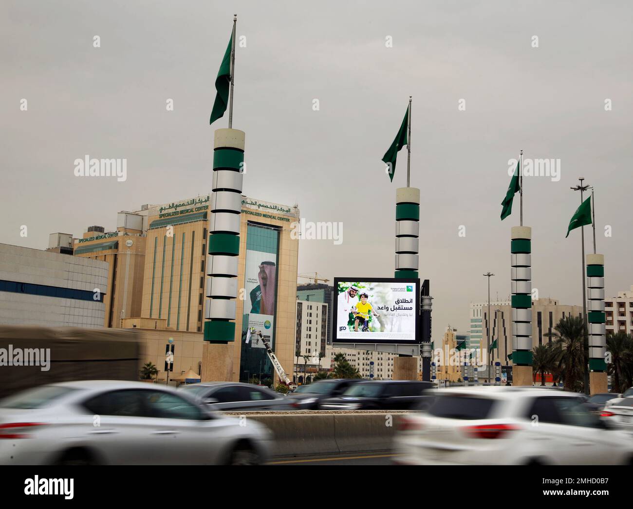 Vehicles pass in front of a screen advertising Saudi Arabia's state ...