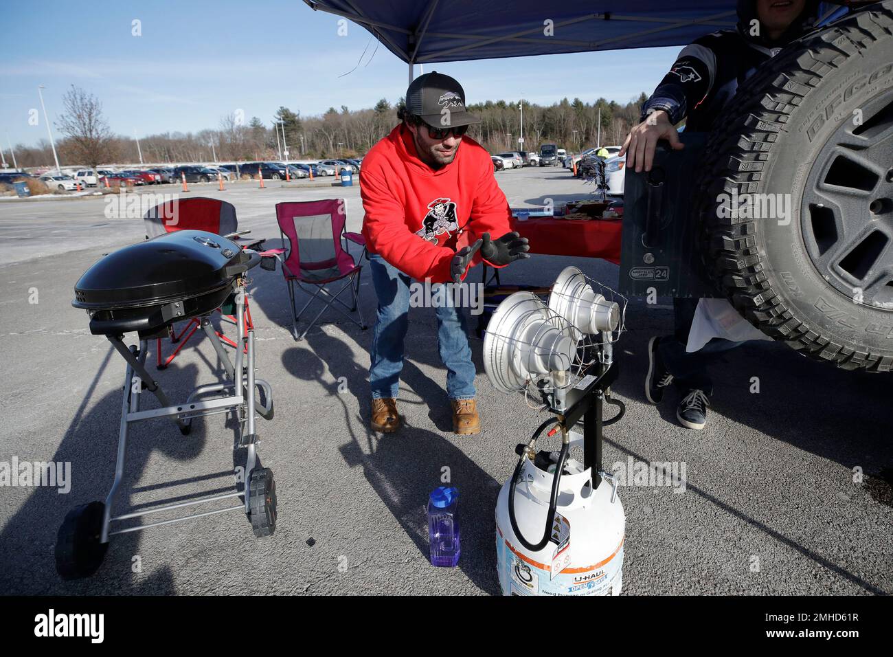 Evan Feldman, of Hull, Mass., warms his hands on a heater while ...
