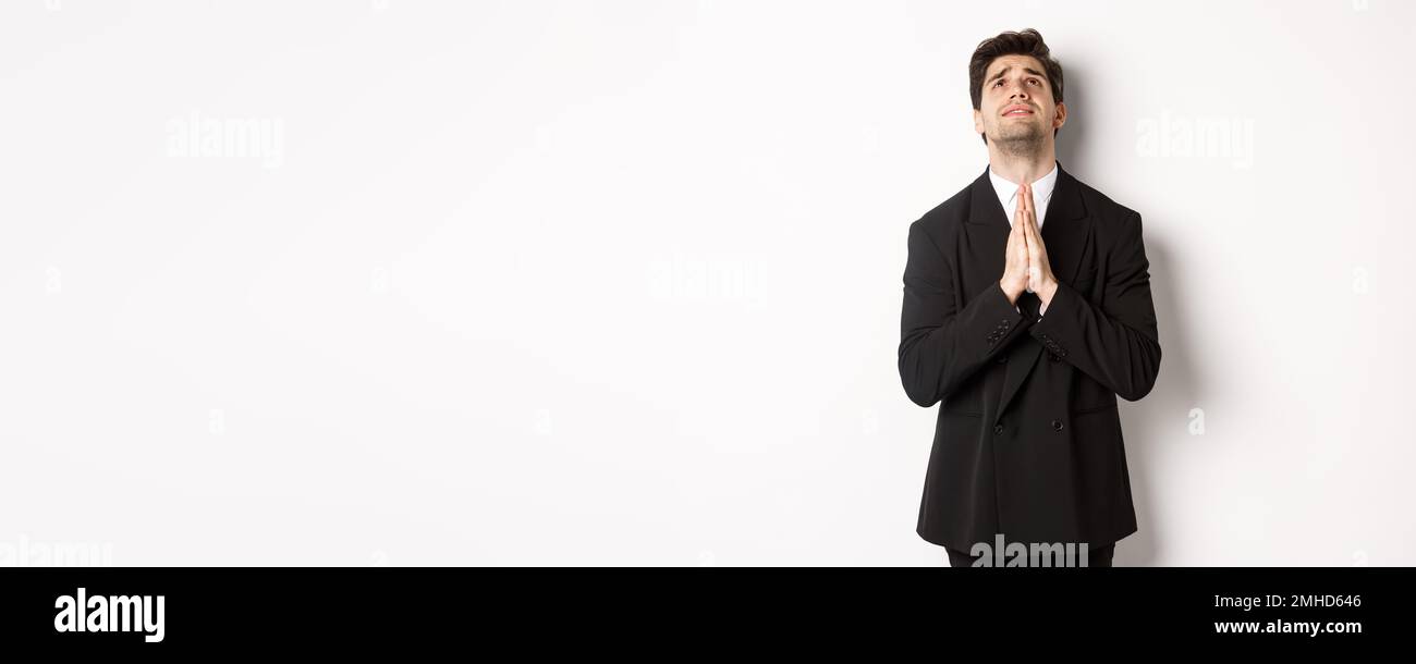 Troubled and hopeful man in black suit begging god, pleading and ...