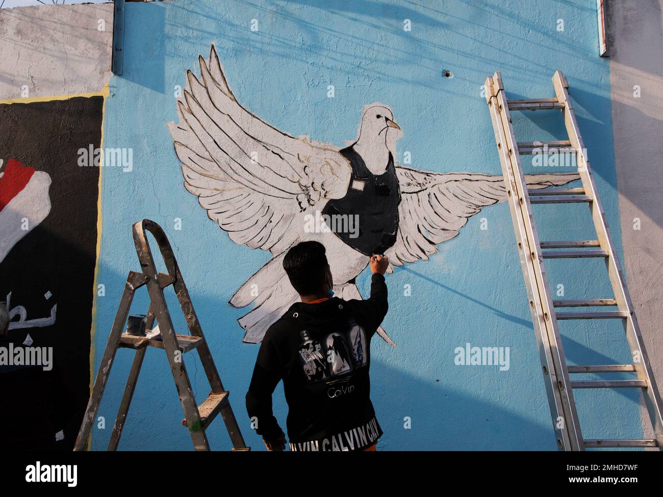 Iraqi street artist Ahmad Raed, 17, works on a mural that depicts a ...