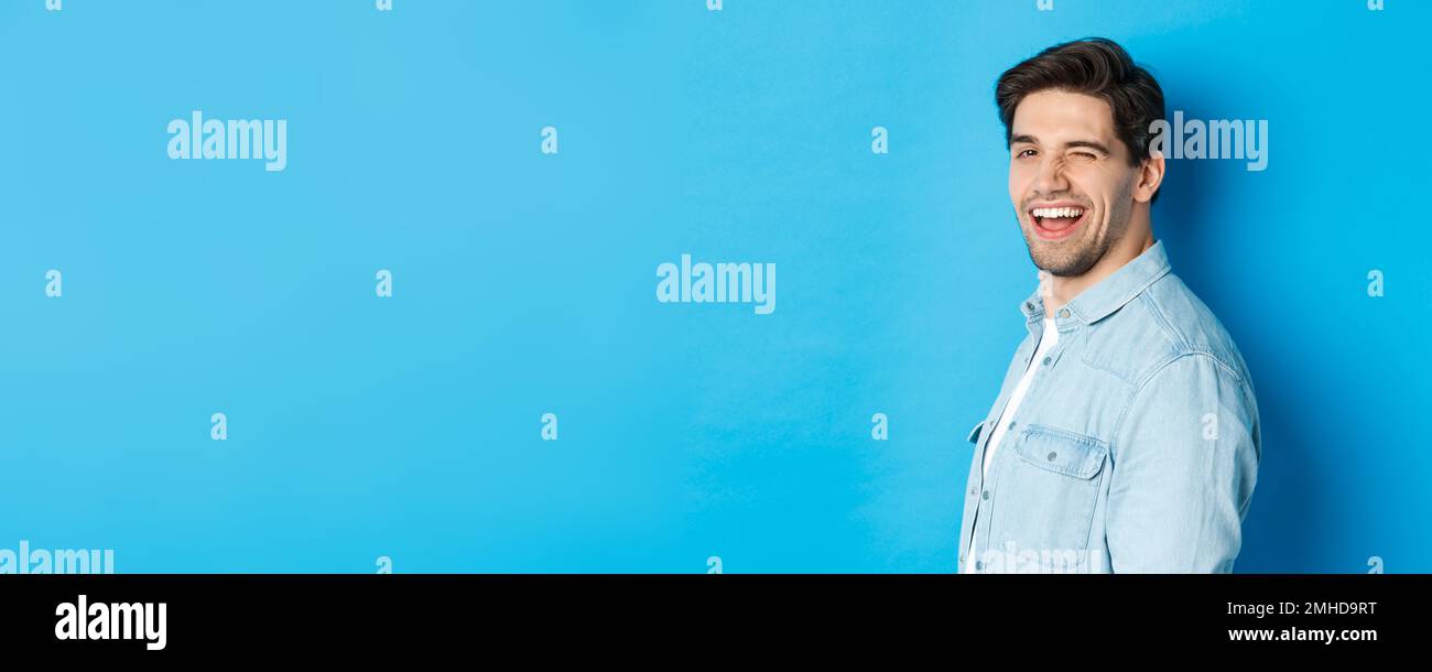 Happy and confident man turn head at camera, winking and smiling ...