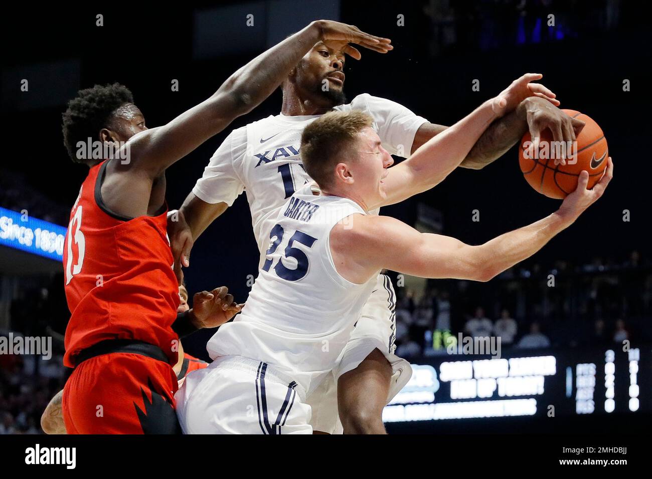 Xavier's Jason Carter (25) and Naji Marshall, center, battle for a ...