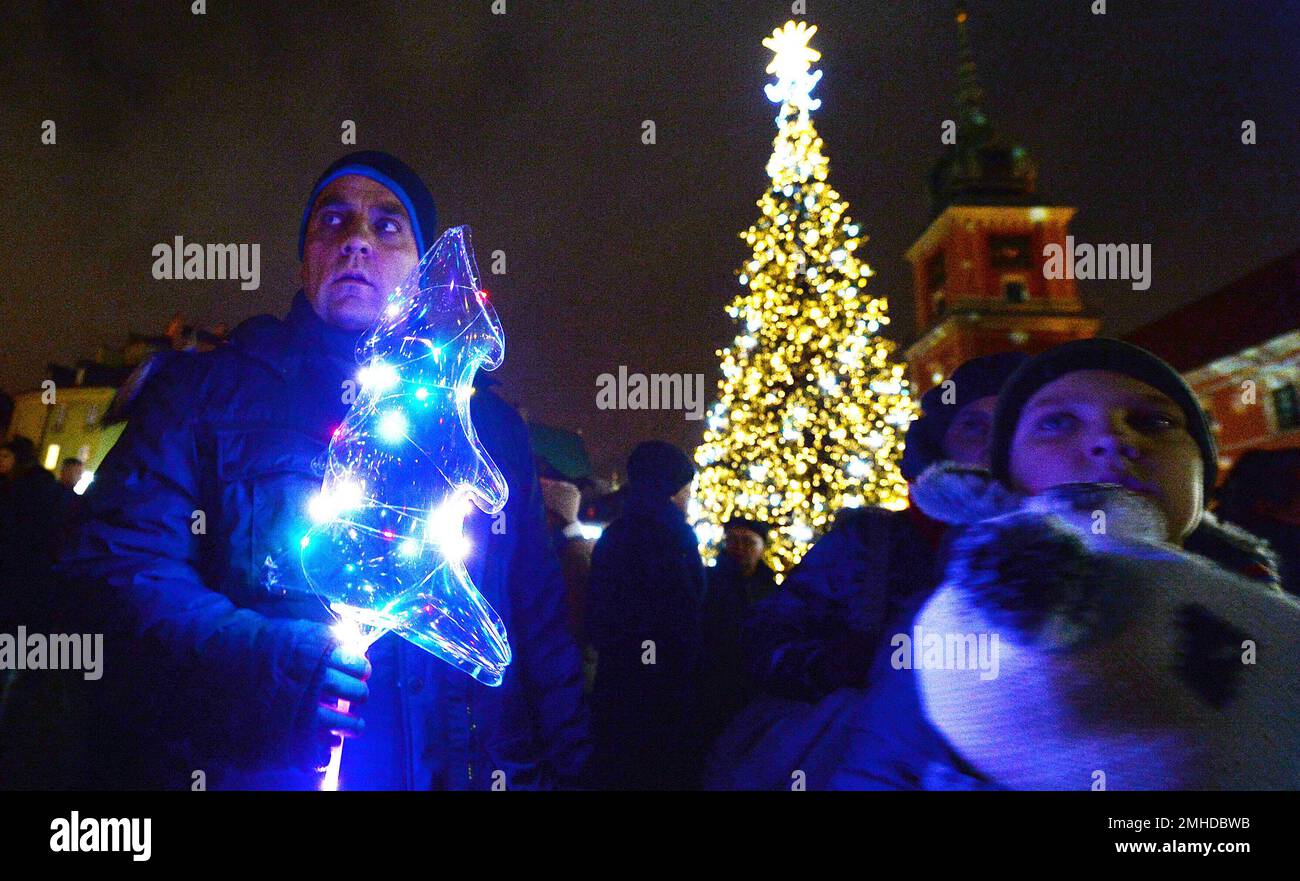 A man holds a transparent balloon shaped like a Christmas tree at a ...