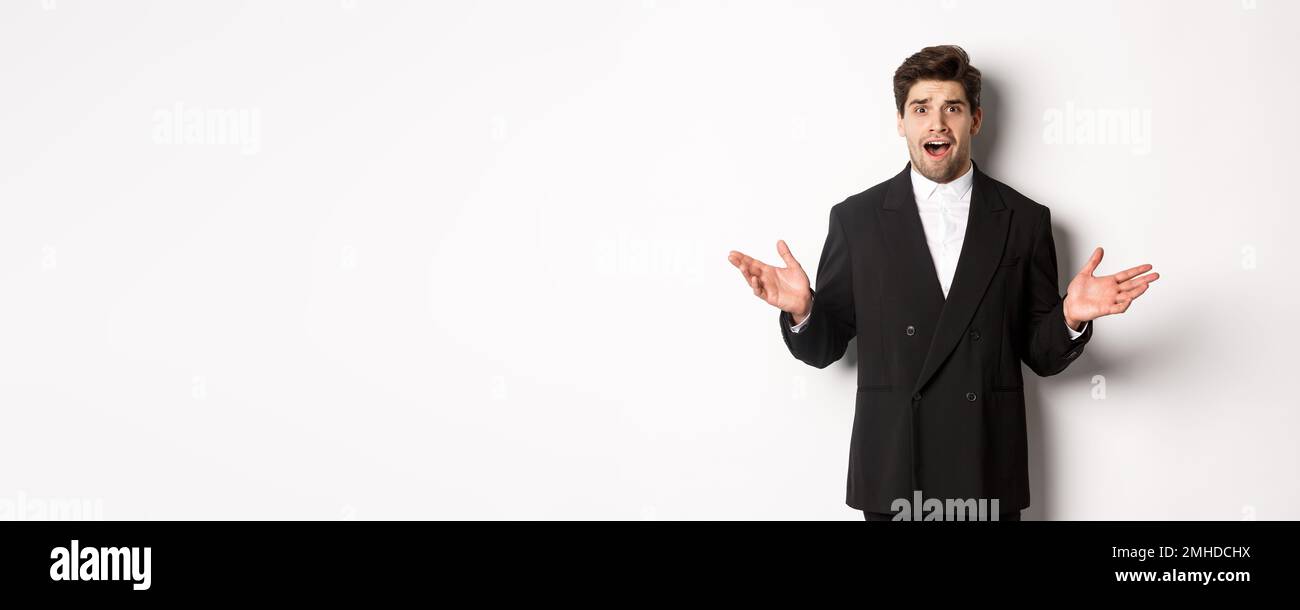 Portrait of confused and worried handsome man in suit, looking at ...