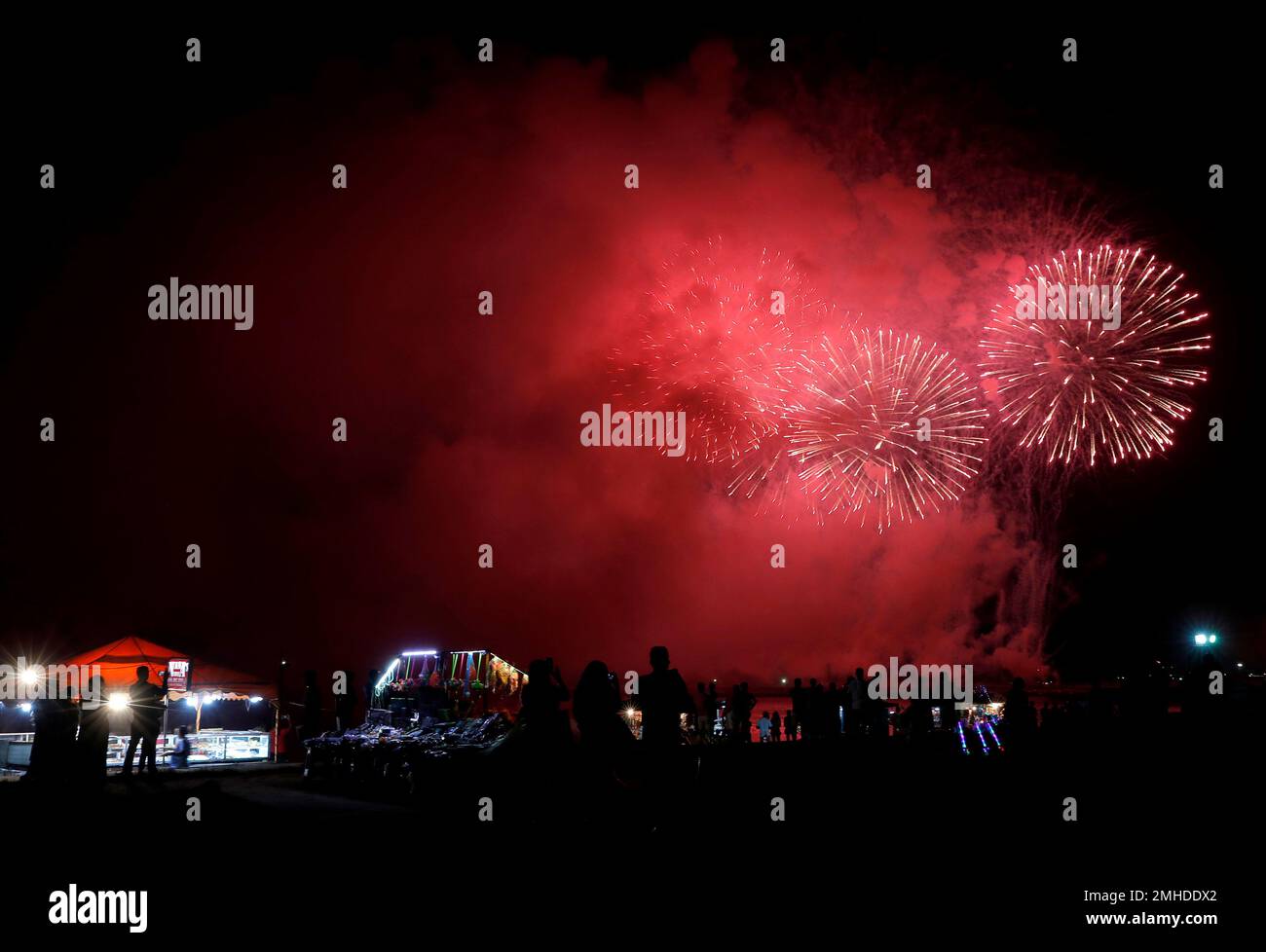 People watch as pyrotechnics go off from the reclaimed land from the ...