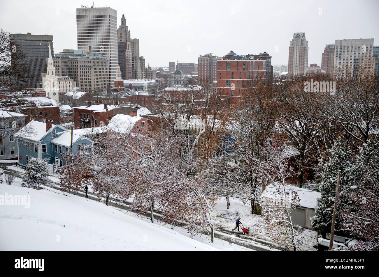 A worker clears away snow from a driveway against the backdrop of ...