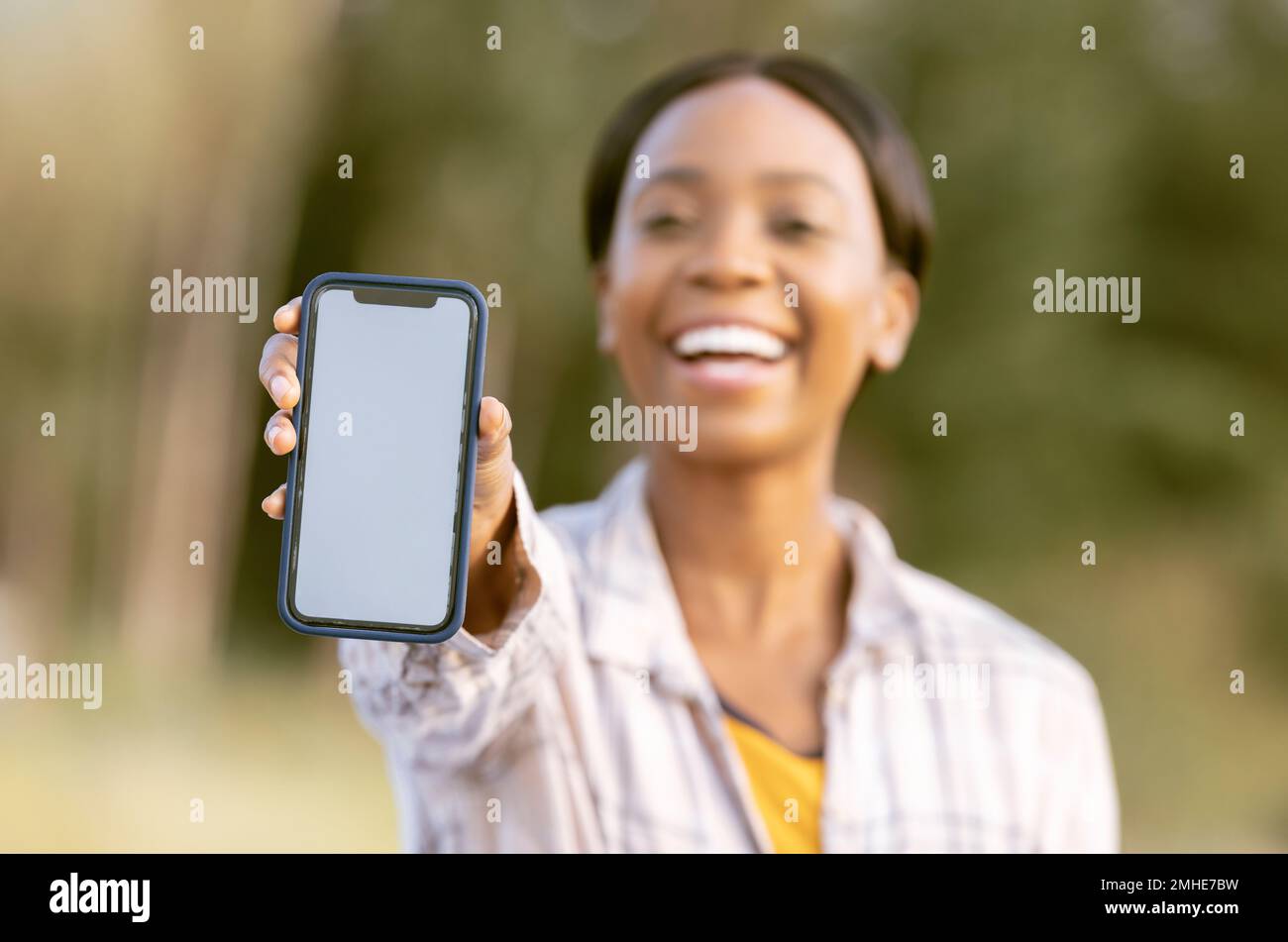 Mockup, smartphone and black woman in nature or park with happy ...