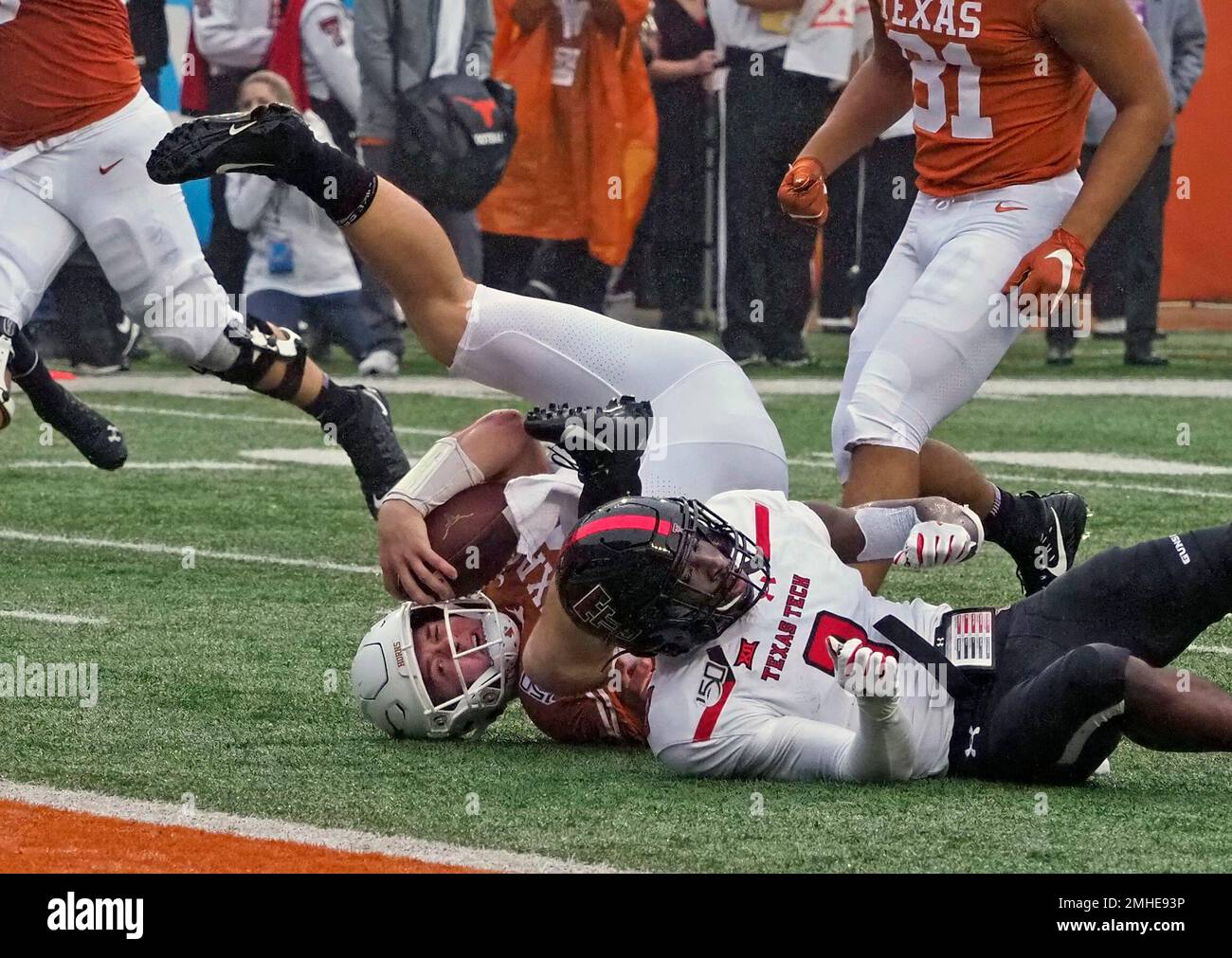 Texas quarterback Sam Ehlinger, back, is upended by Texas Tech's ...