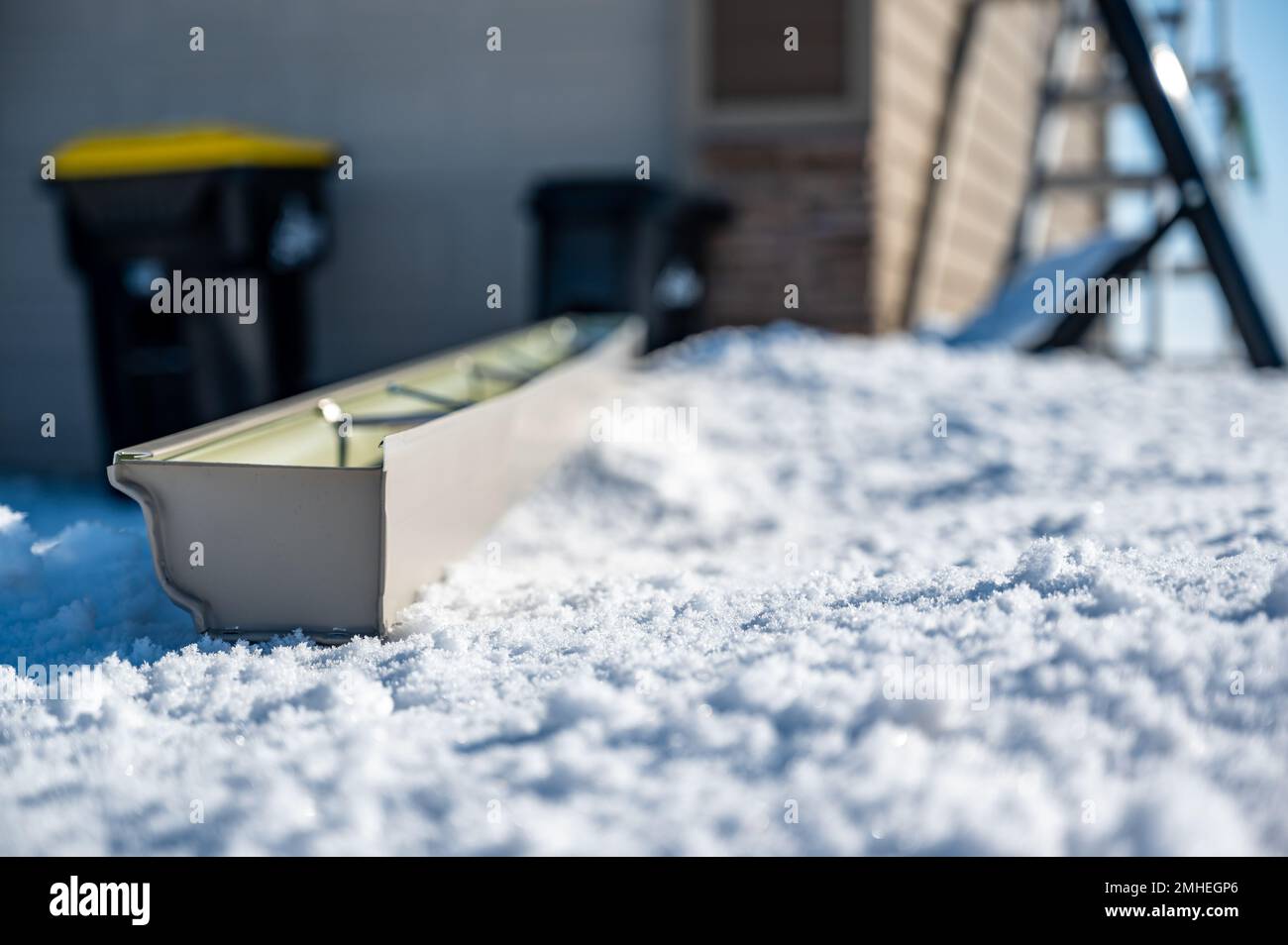 Section of new metal gutters laying on the ground with snow ready for ...