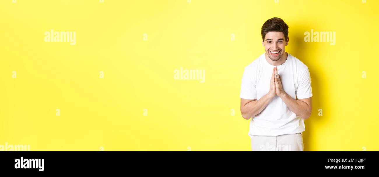 Handsome guy saying thank you, bowing and holding hands in namaste ...