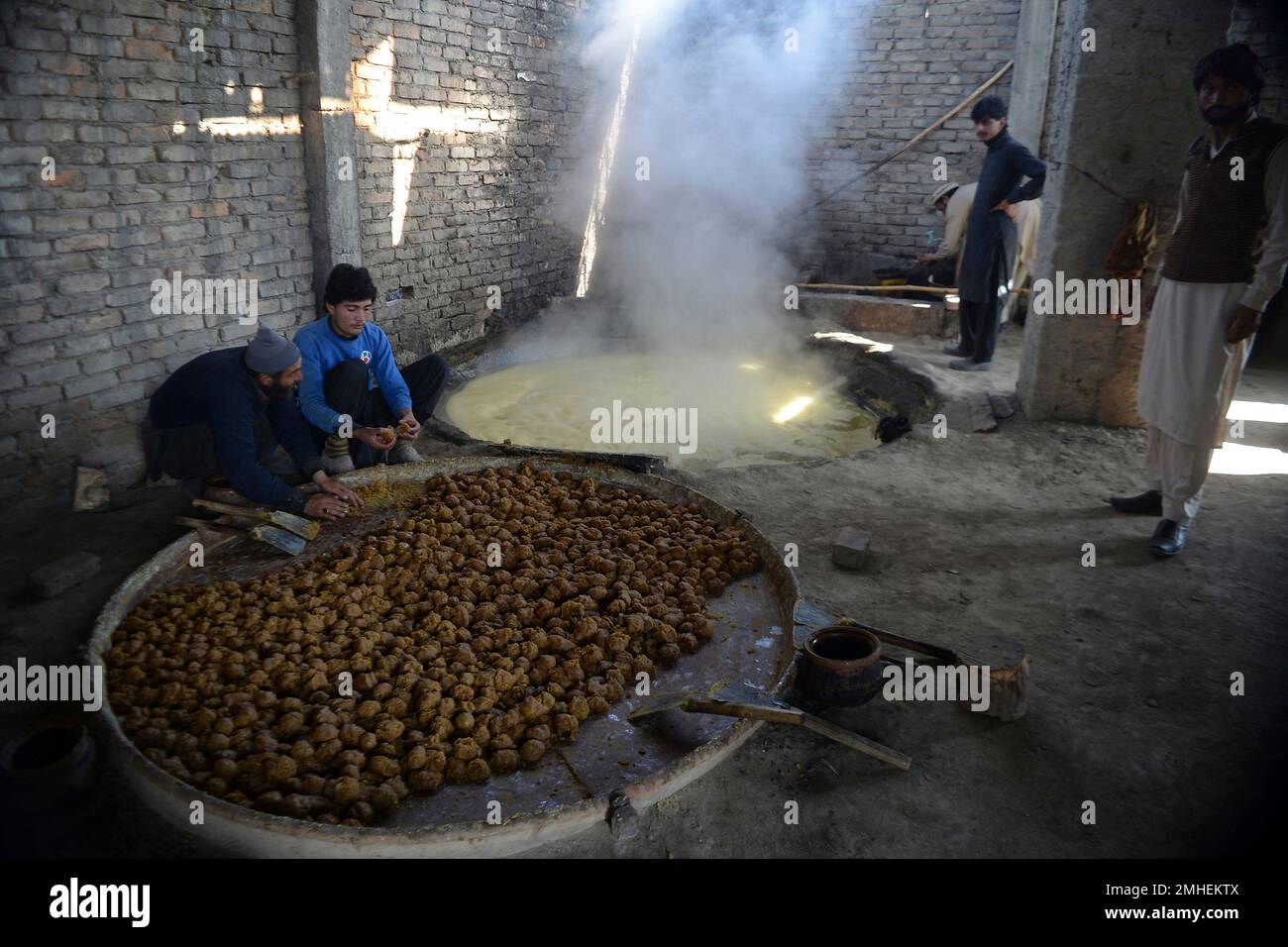 Pakistani farmers boil sugarcane juice and then make balls by hand to ...