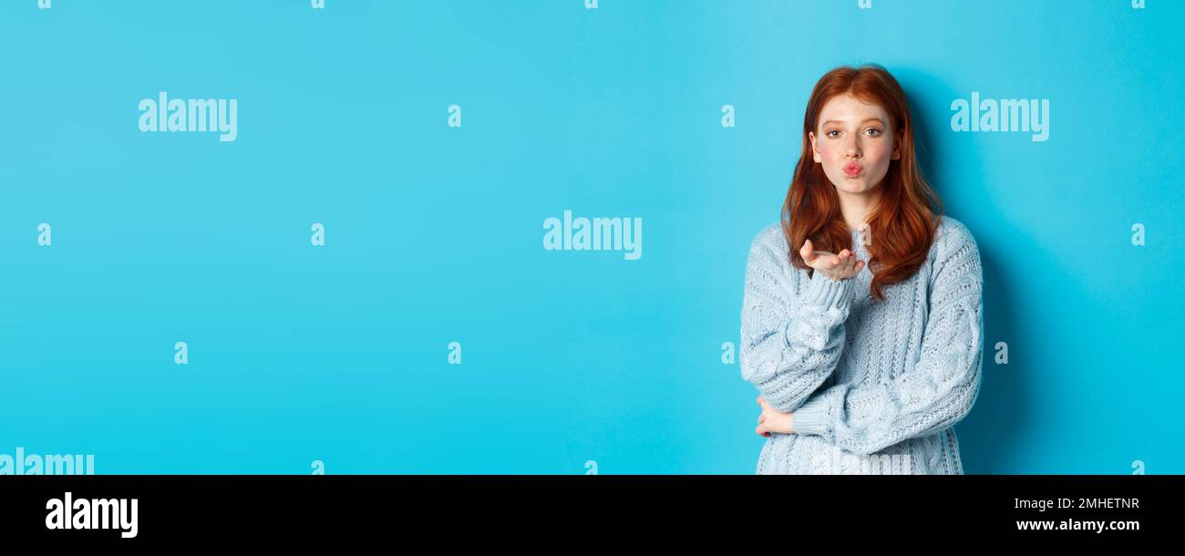 Lovely teen girl in sweater blowing air kiss, pucker lips and staring ...