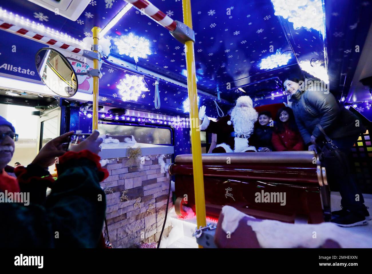 Passengers take a photo with Santa in a CTA Holiday bus at a bus stop ...