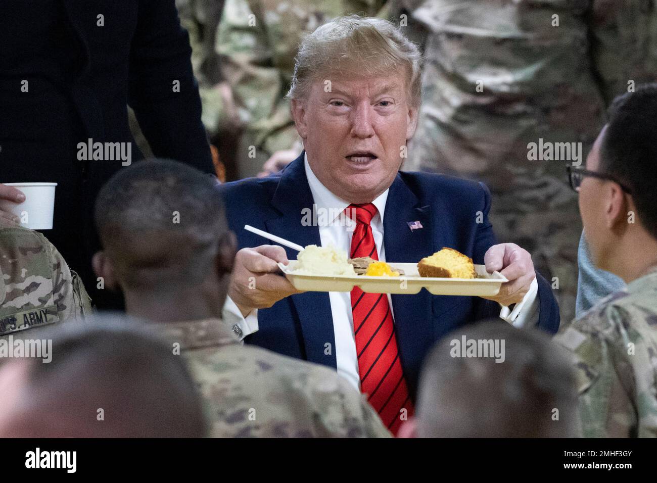 President Donald Trump holds up a tray of Thanksgiving dinner during a ...