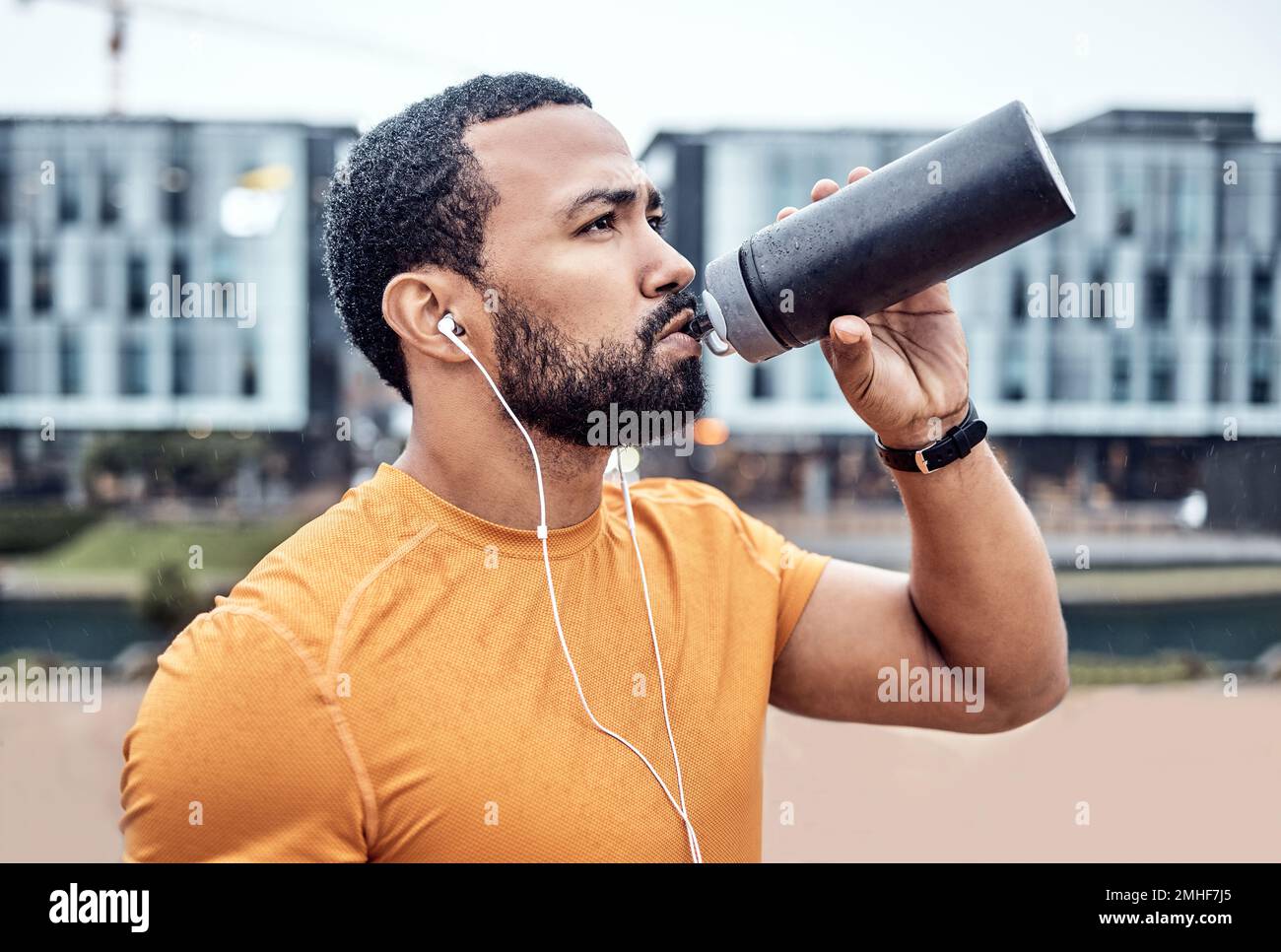 Fitness, athlete and man drinking water in the city after running for ...