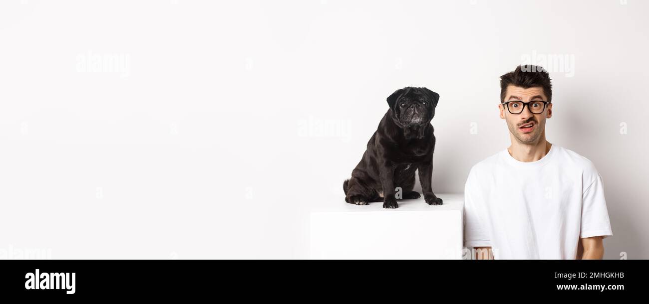 Image of hipster dog owner sitting near cute black pug, staring at ...