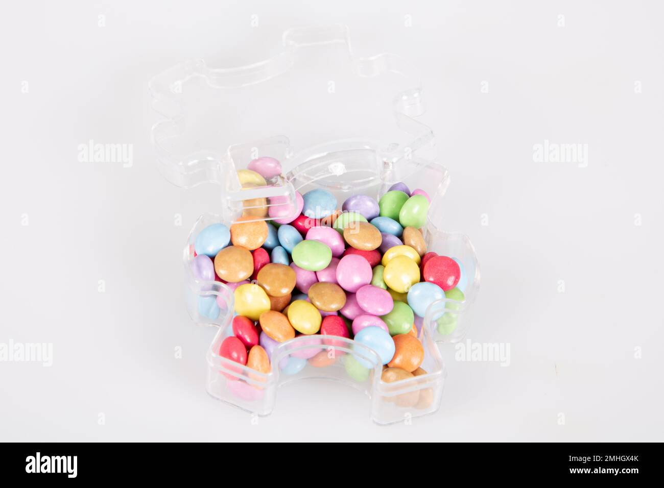 Round multi-colored sweets in plastic puzzle box on a white background ...