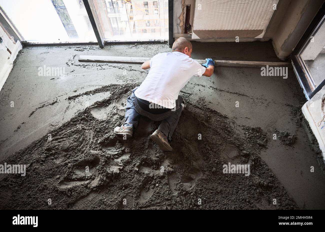 Top view of male construction worker using screed rail while screeding ...