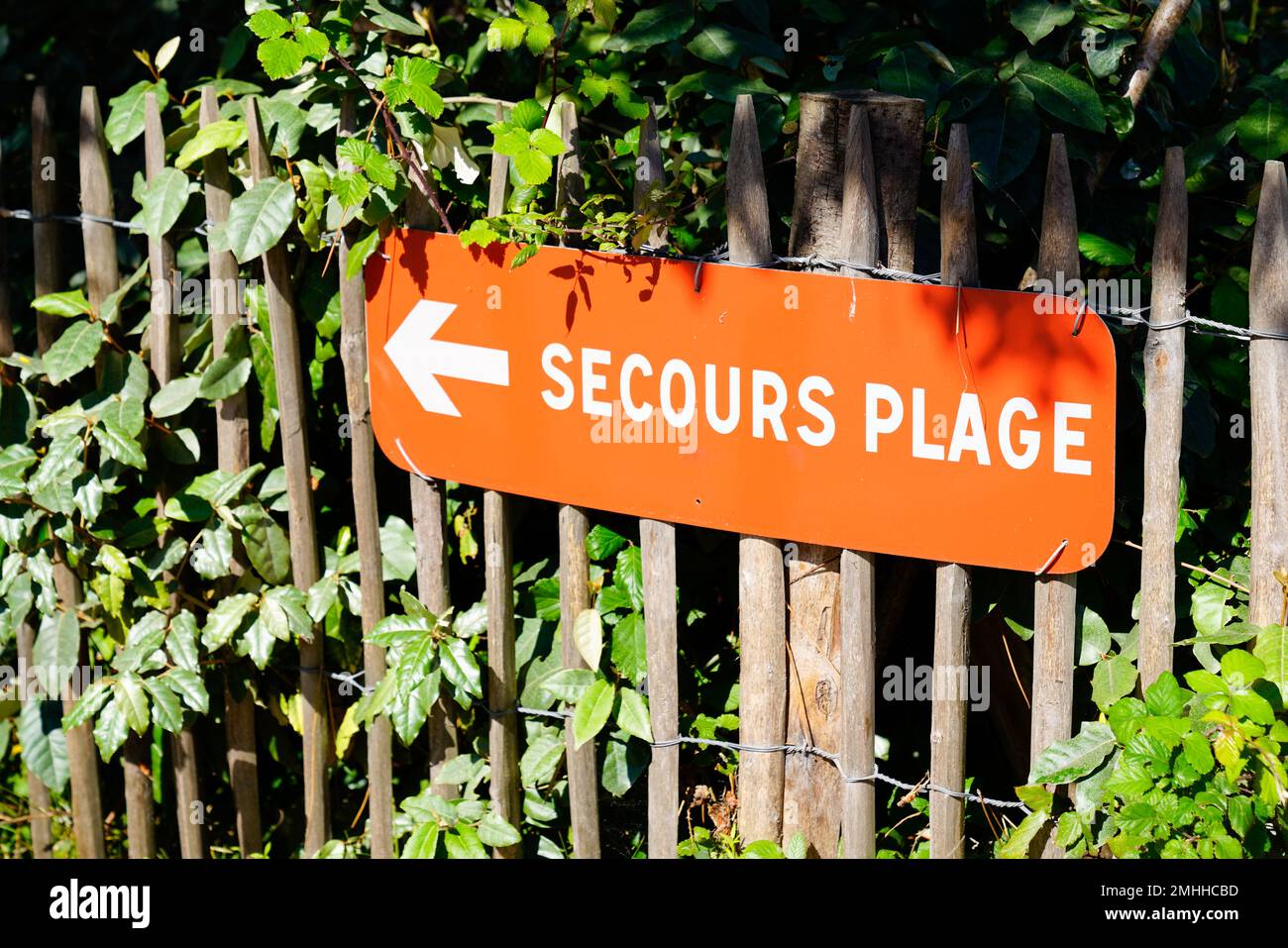 arrow road sign indicates the lifeguard station on the beach in french ...
