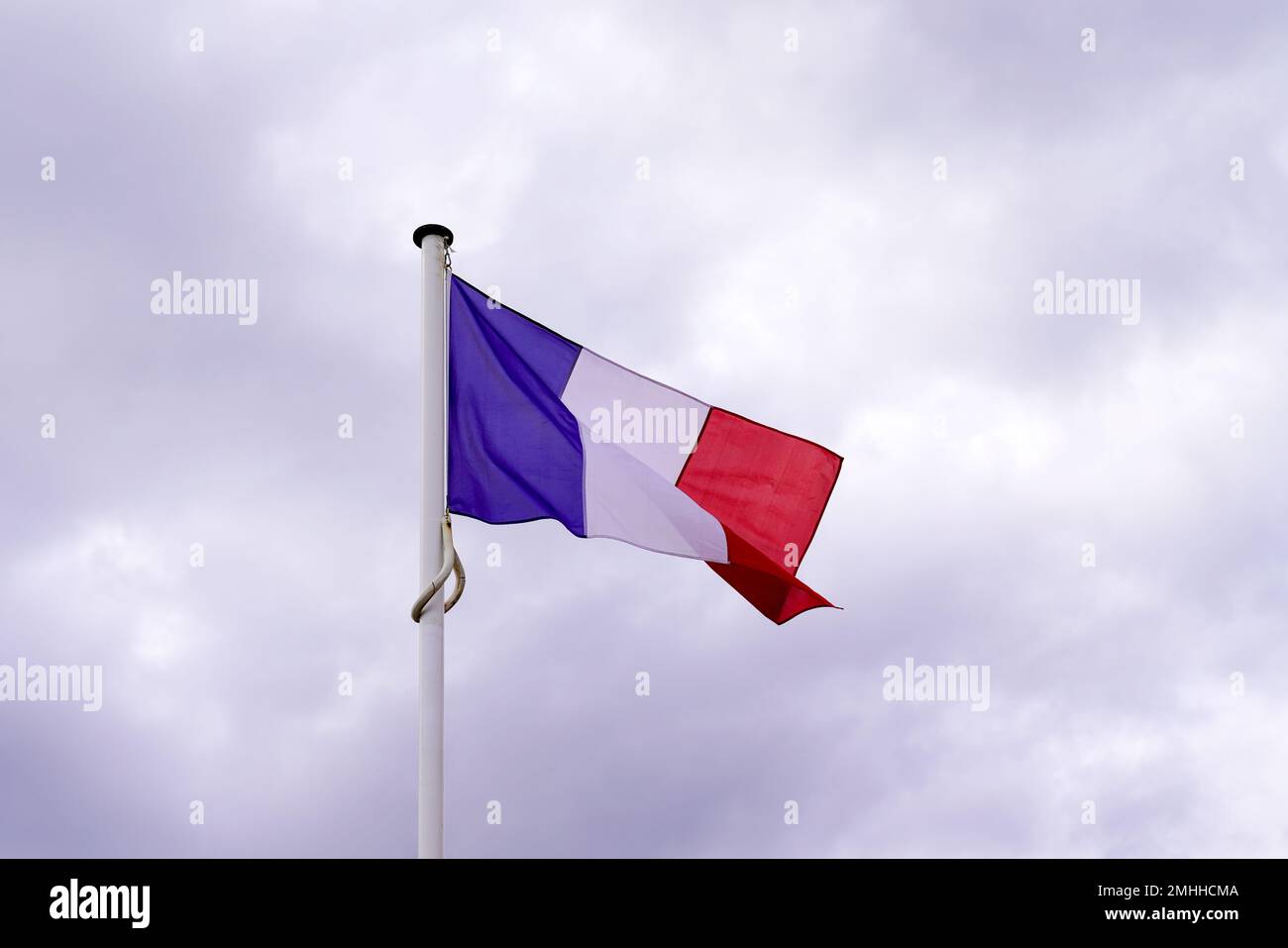 French tricolors blue white red flag waving front on cloudy sky in town ...
