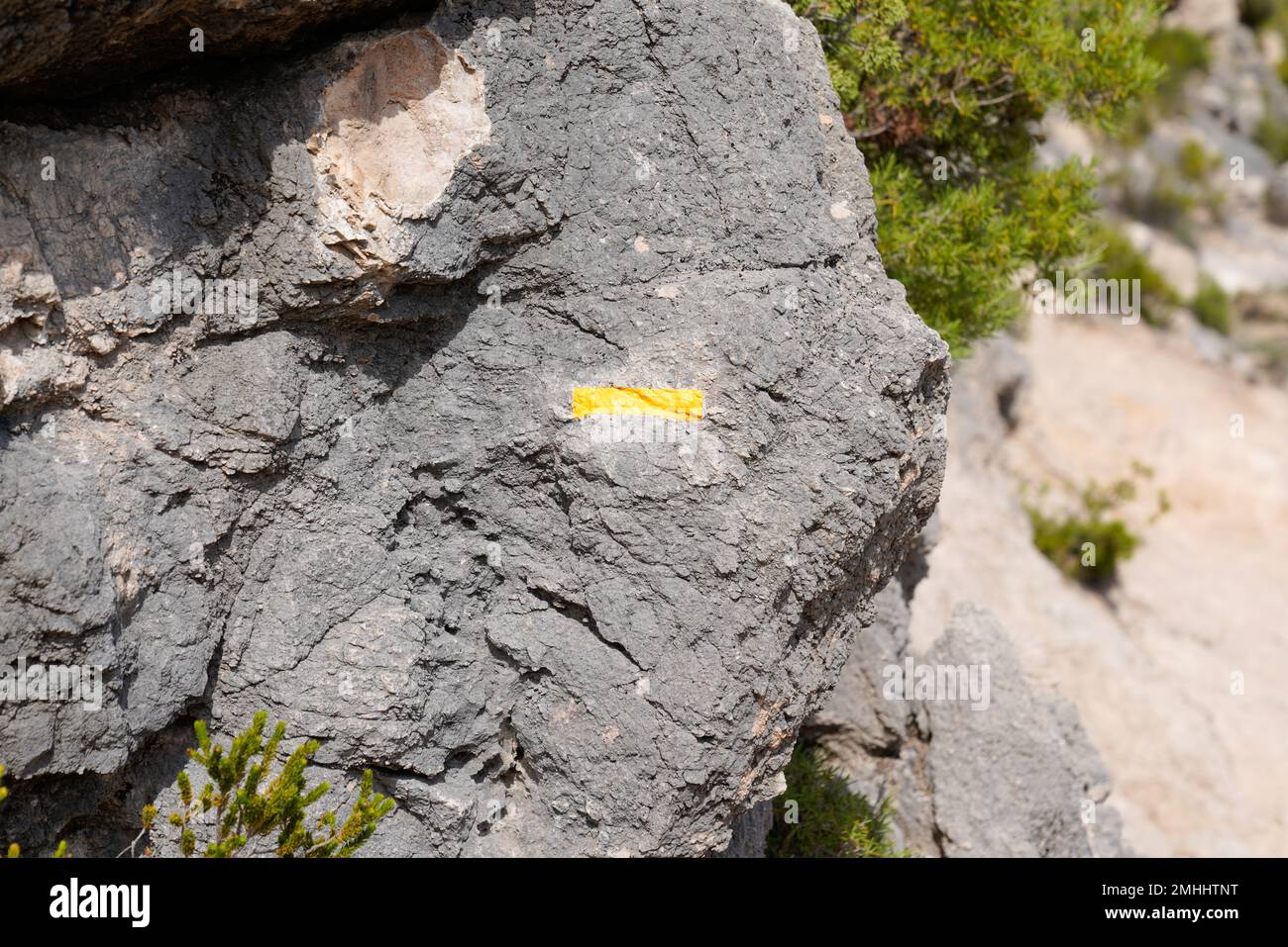 Hiking Trail path Marker on a stone with yellow signs drawn paint sign ...