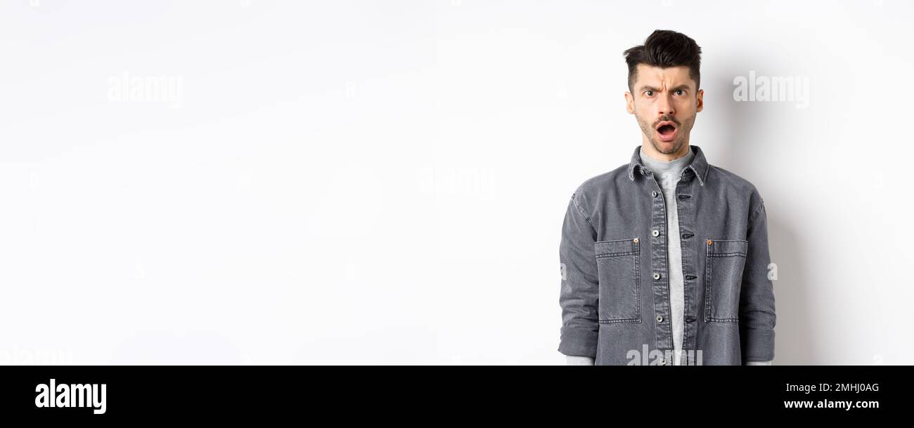 Shocked and offended man frowning, looking at camera with opened mouth ...