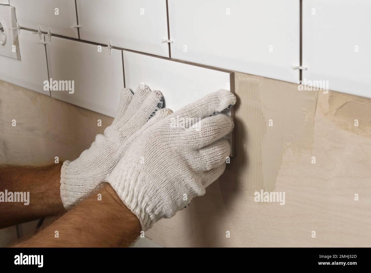 Male Worker Master Laying Ceramic Tiles on the Wall of Kitchen ...