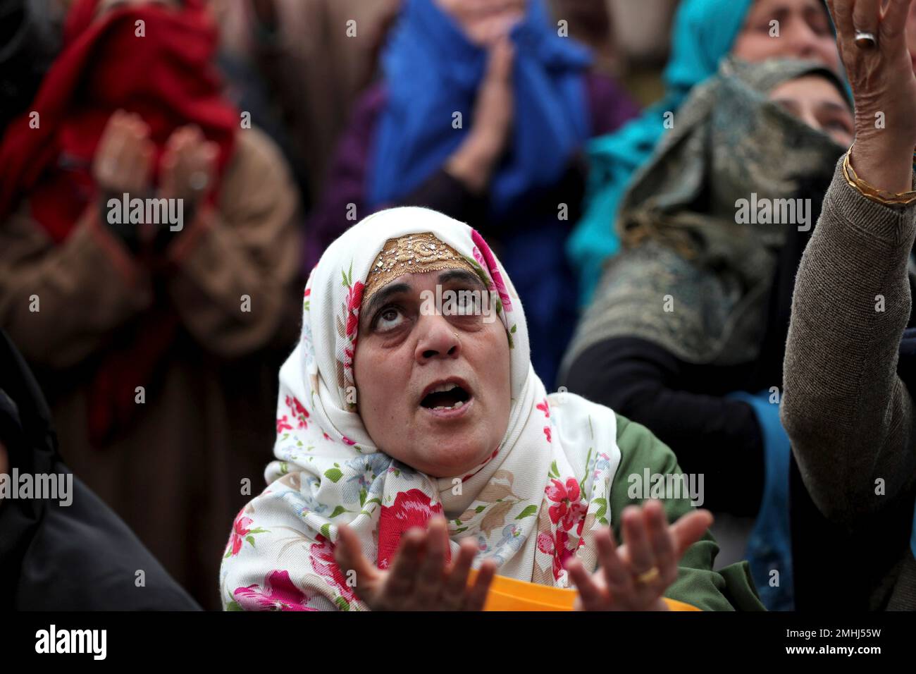 A Kashmiri Muslim woman prays as the head priest, unseen, displays a ...