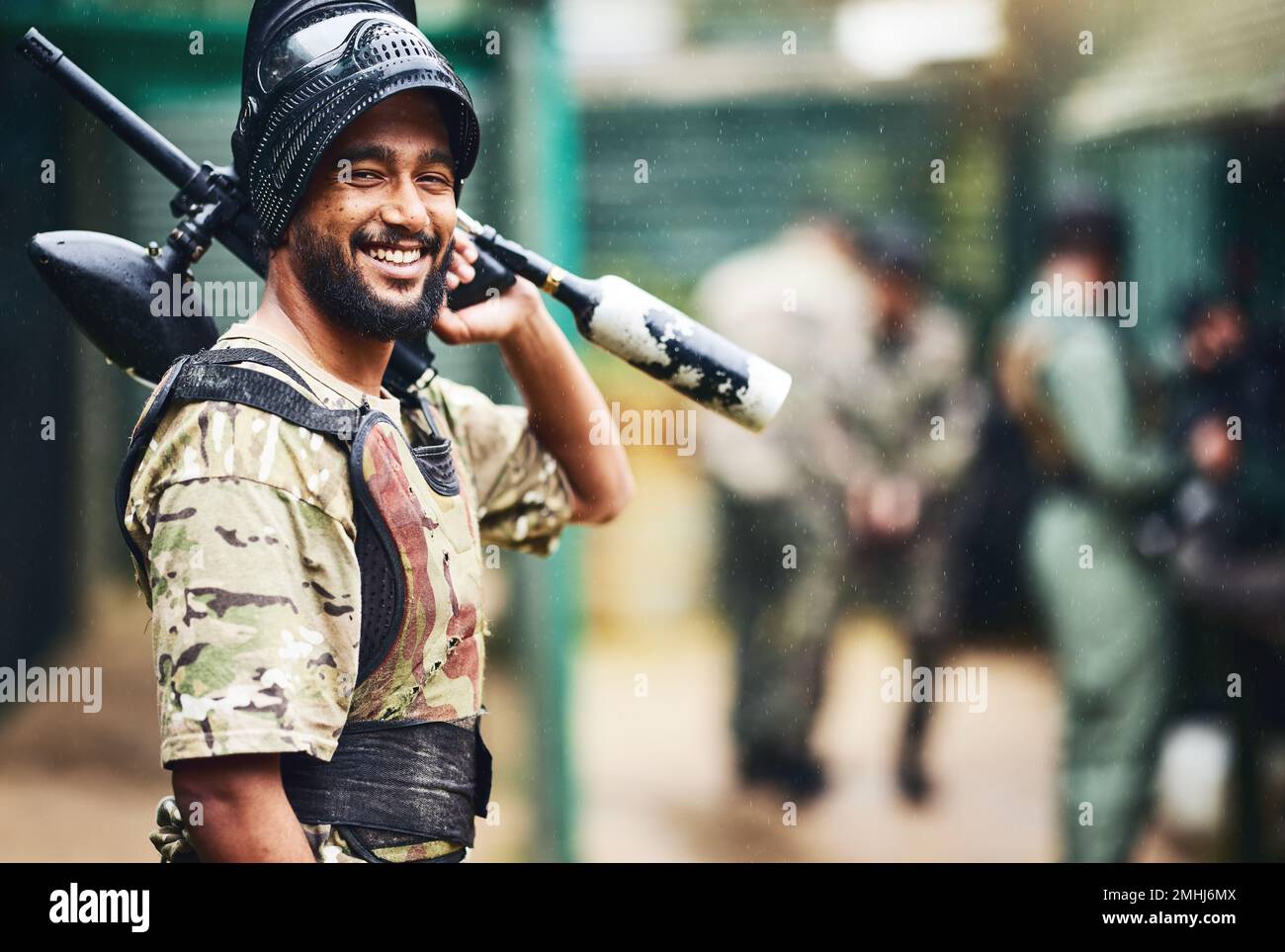 Smile, portrait or man and paintball gun in games arena, teamwork ...