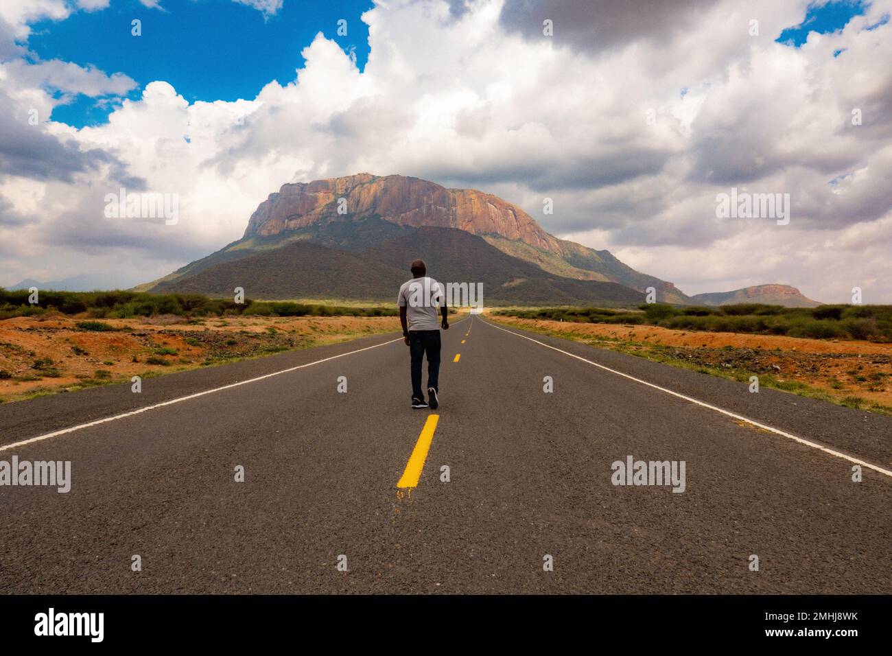 A man on an empty highway against the background of Mount Ololokwe in ...