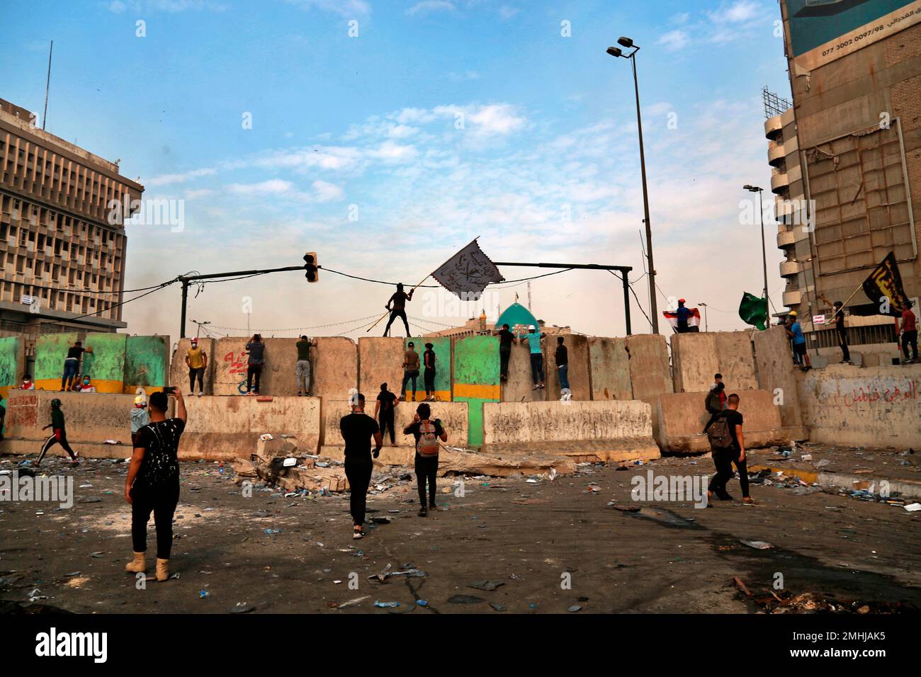Protesters climb on a concrete wall placed by Iraqi security forces ...